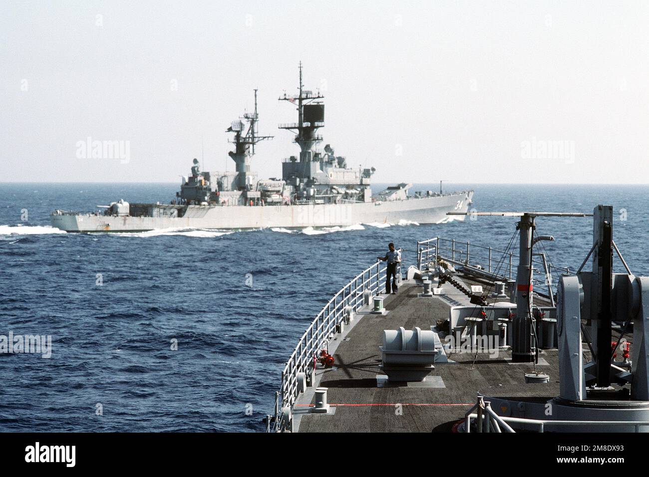 The guided missile cruiser USS BIDDLE (CG-34) passes near the bow of the nuclear-powered guided ...