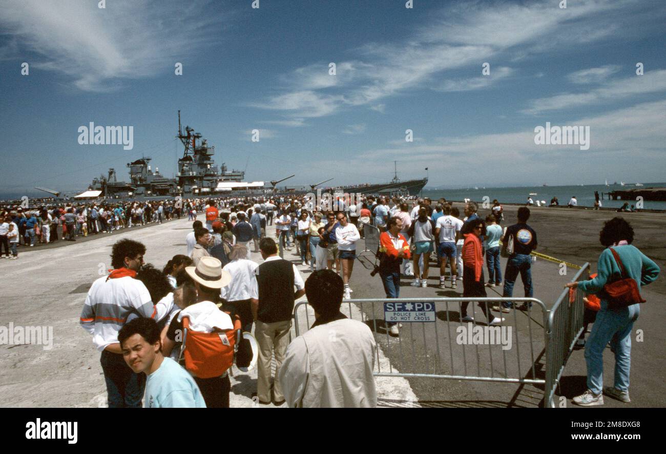 Hundreds of people stand in line on the pier, waiting to tour the ...