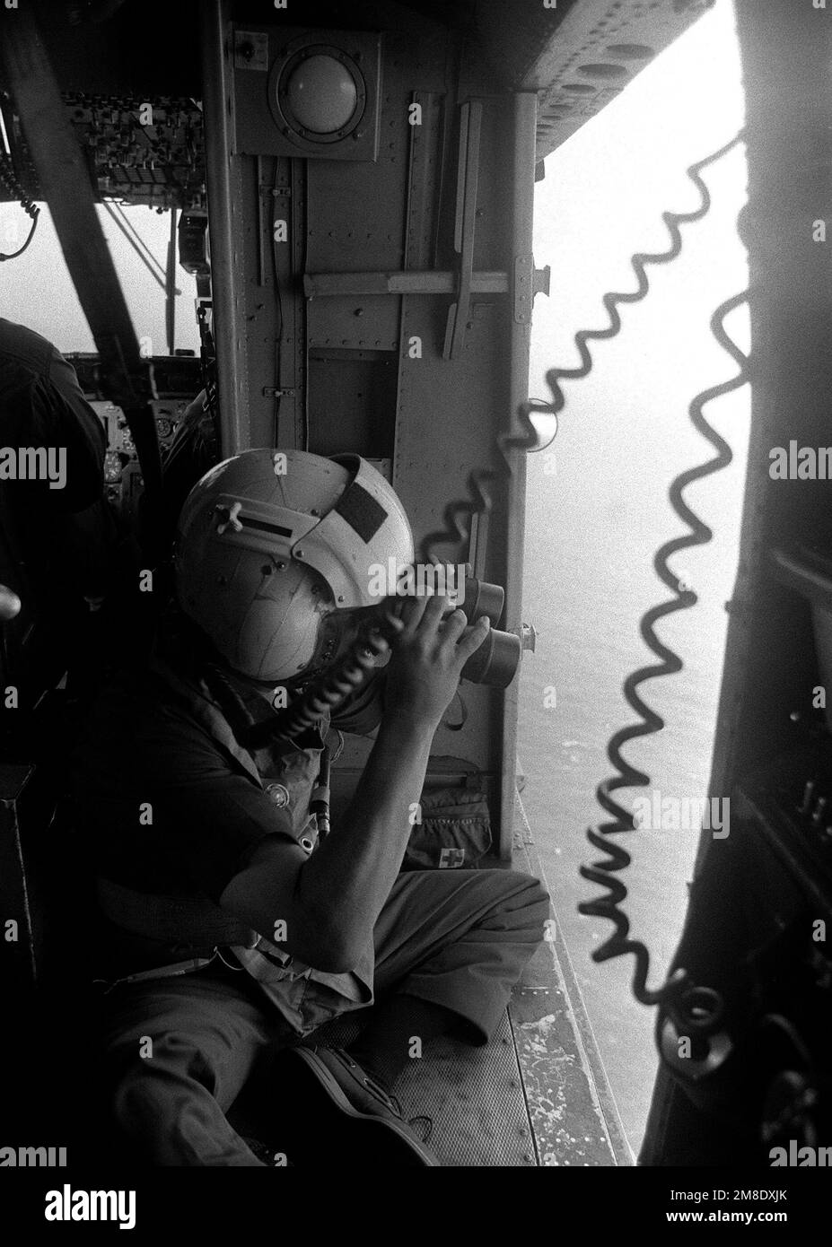 A member of a law enforcement team observes a passing ship from the ...