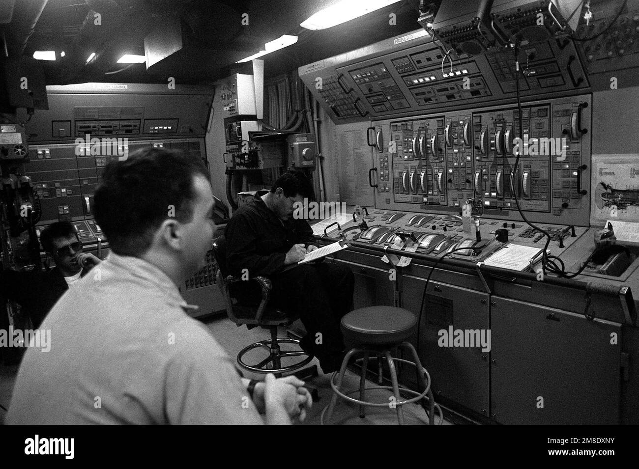 Crew members monitor the propulsion control console aboard the guided ...