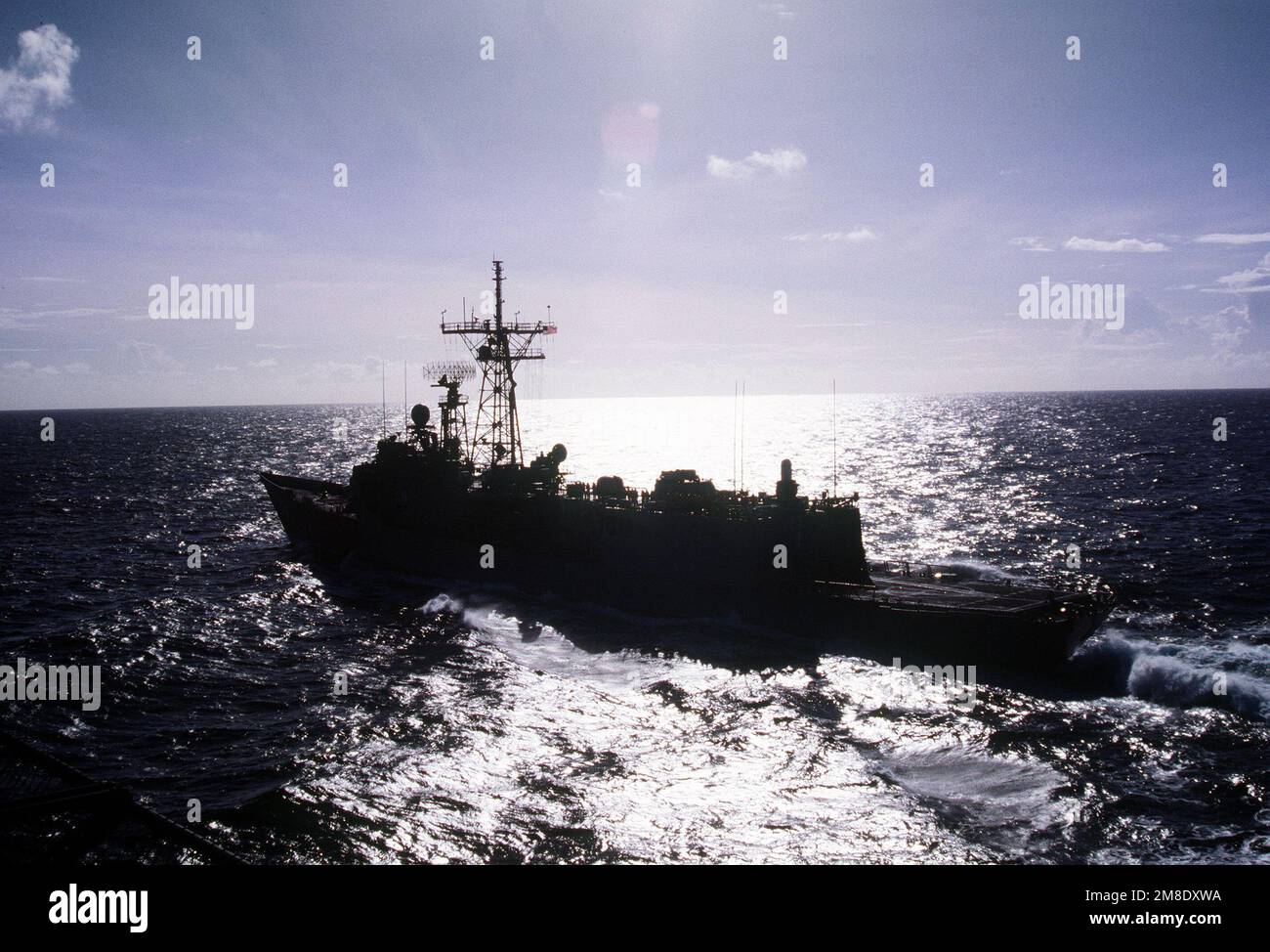 A silhouetted port quarter view of the guided missile frigate USS DOYLE ...