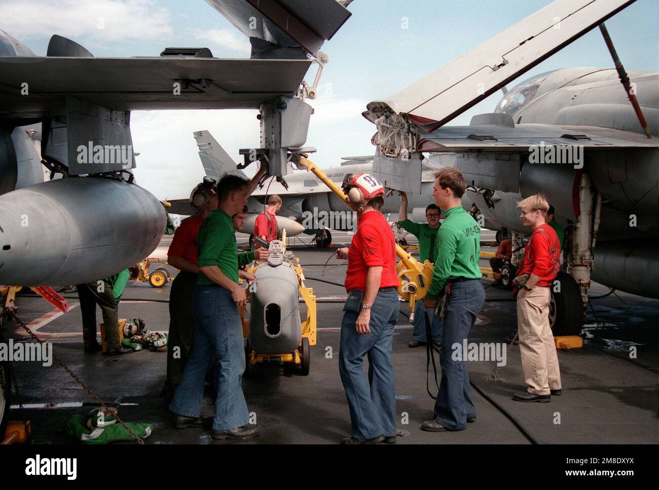 Flight deck crew members and ordnance crew members remove an electronic ...