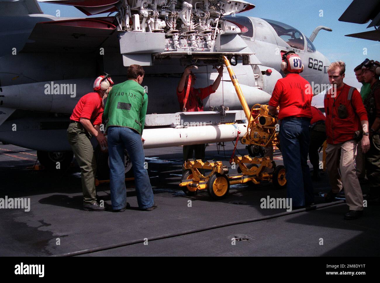 Flight deck crew members and ordnance crew members use an HLU-196 bomb ...