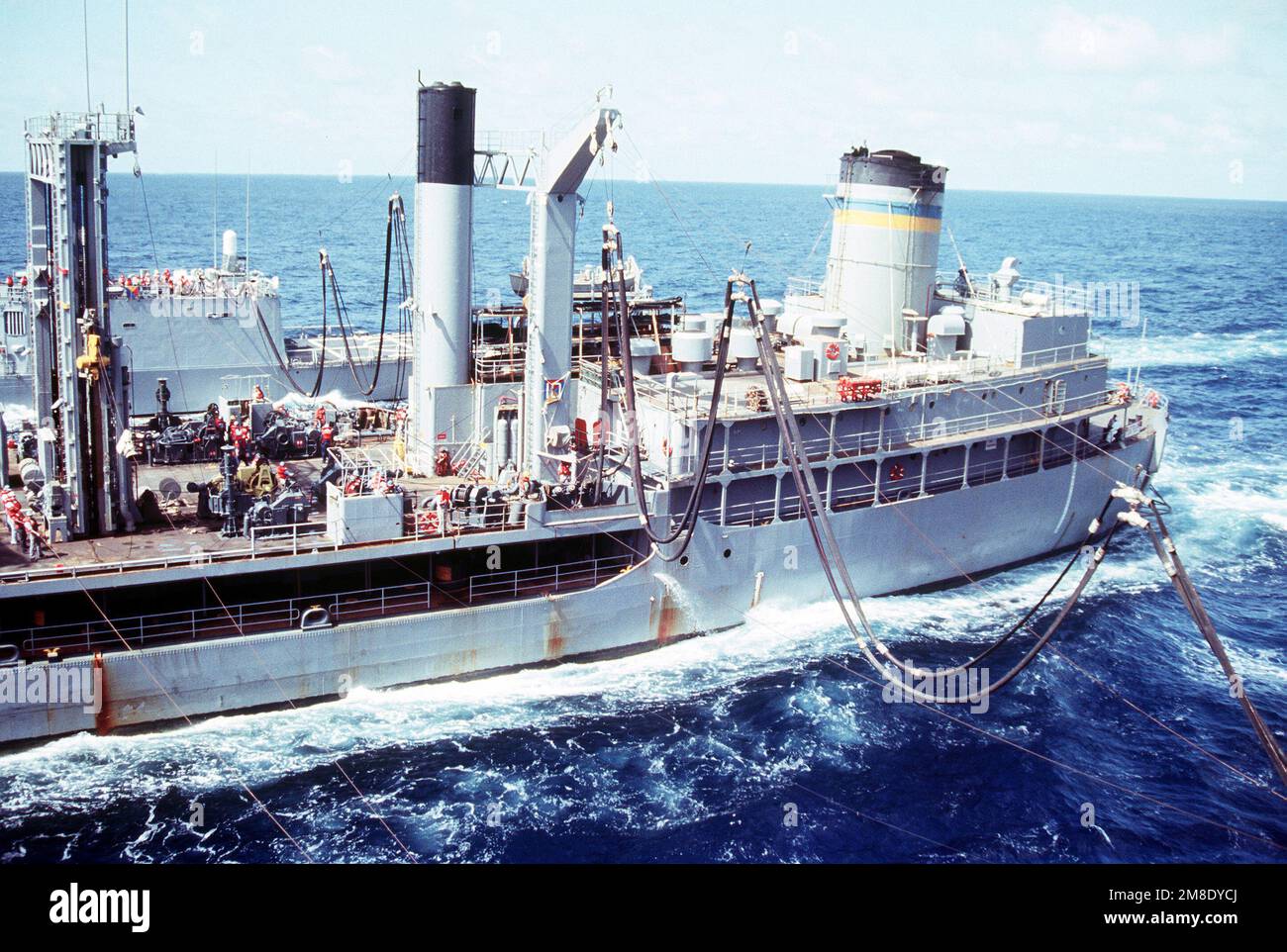Refueling hoses extend from another ship to the kingpost of the fleet ...