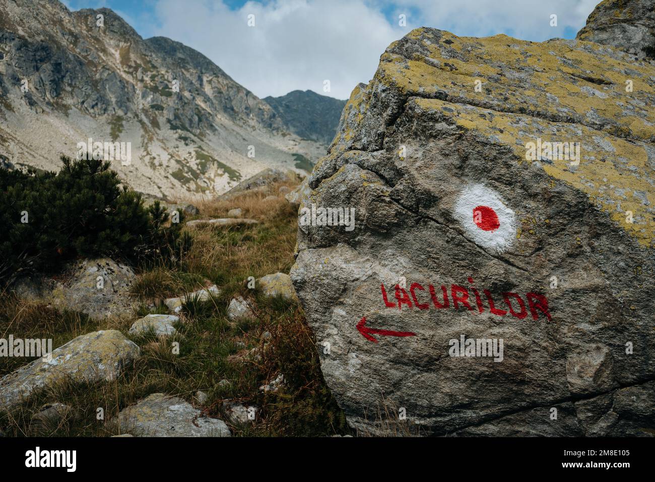 A red Romanian sign means "lake" on a rock with direction arrow in ...
