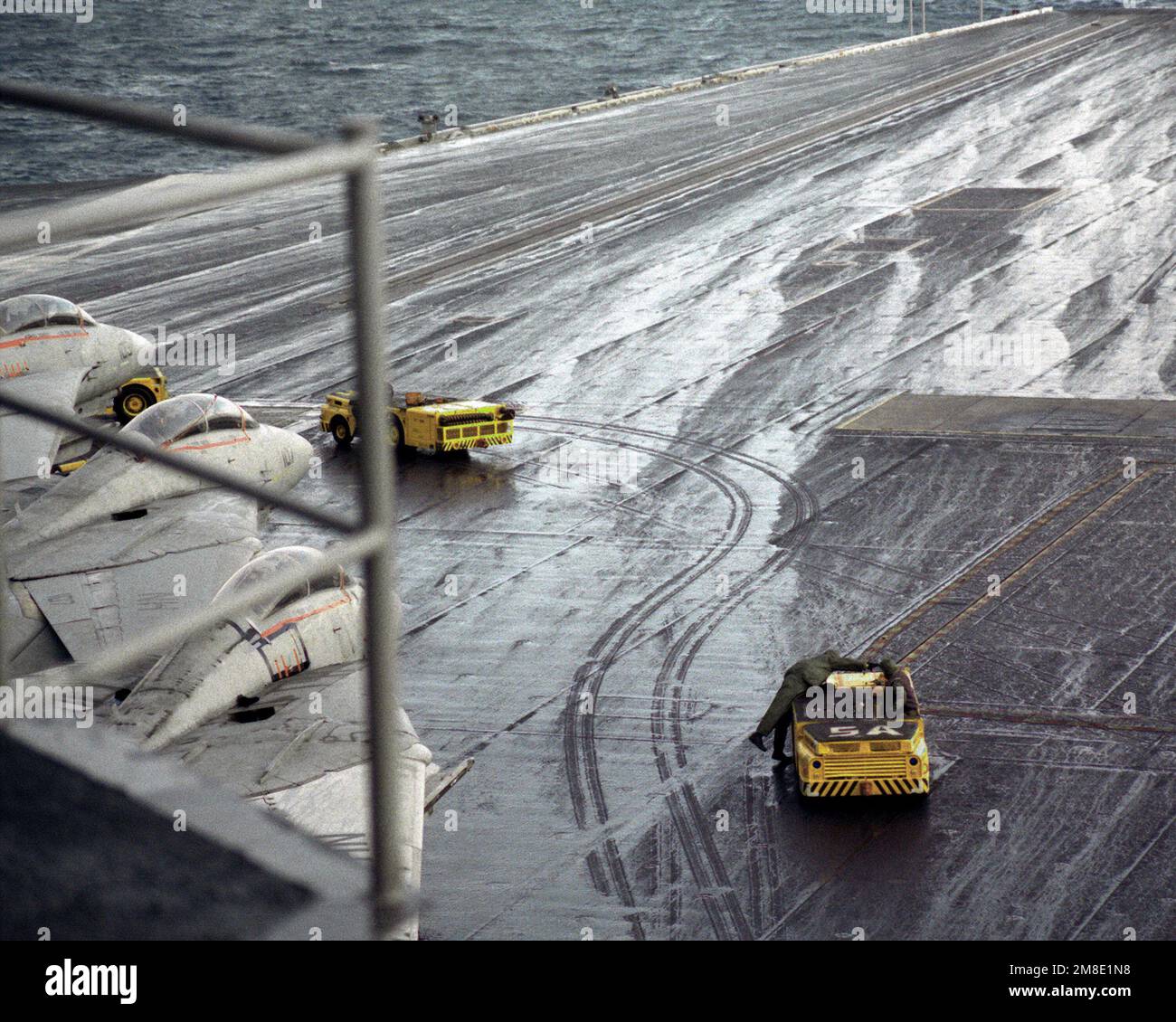An MD-3A tow tractor leaves tracks as rain and wind produce an icy ...