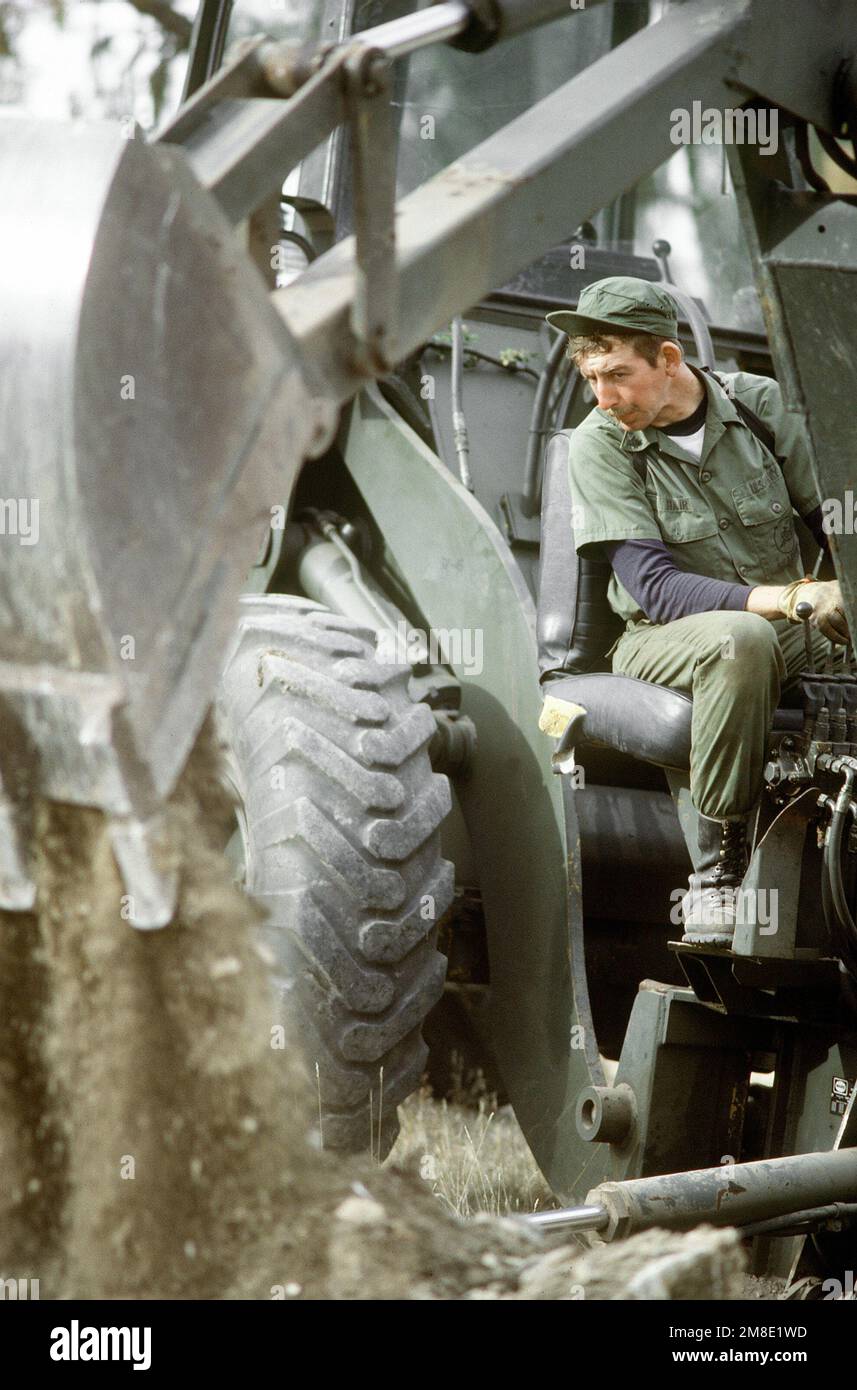 A member of a U.S. Navy construction battalion operates a backhoe ...