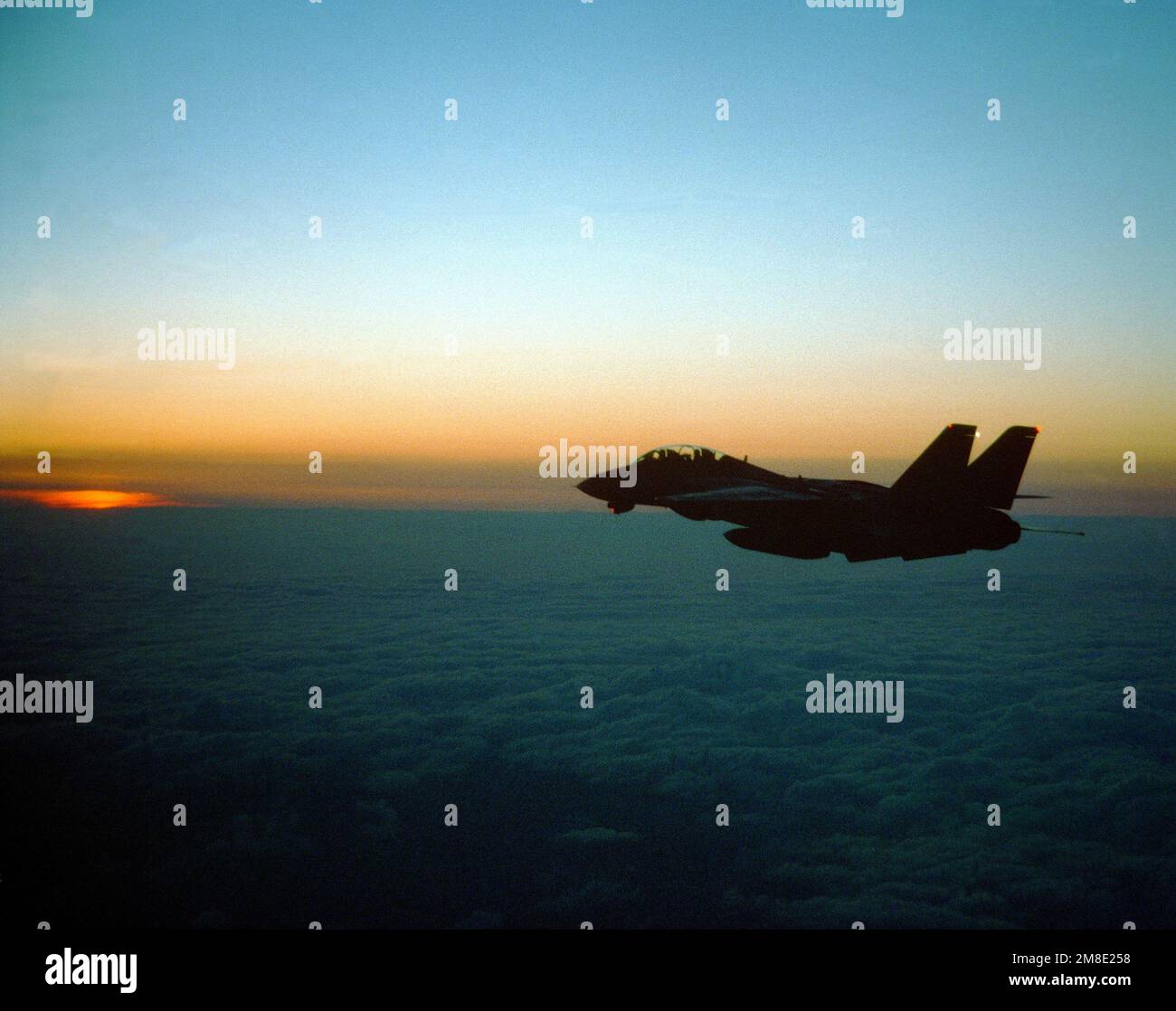 A Fighter Squadron 33 (VF-33) F-14A Tomcat aircraft is silhouetted ...