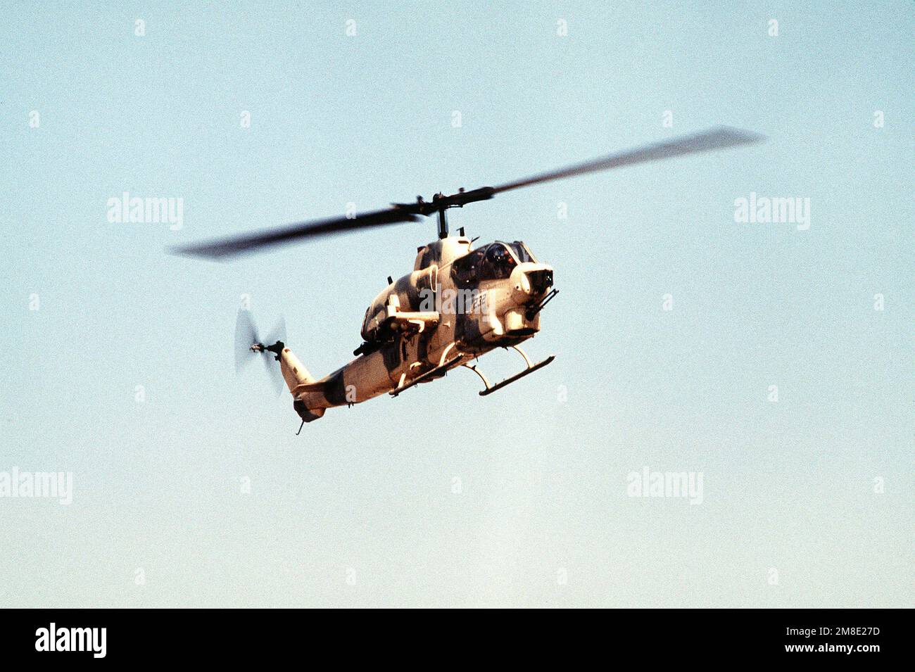 A Marine Corps AH-1W Sea Cobra helicopter passes over the city's ...