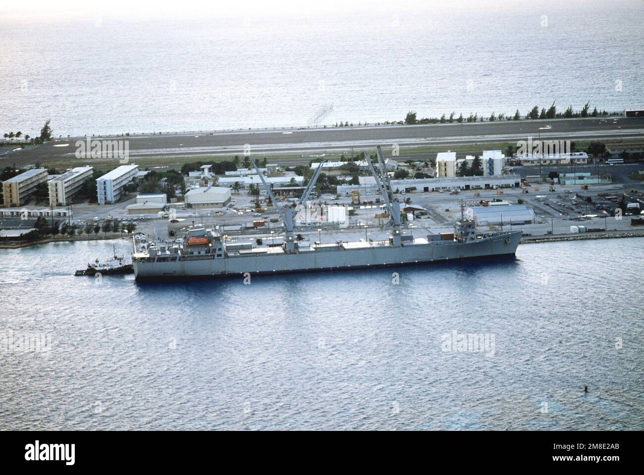 A tug boat follows the Military Sealift Command auxiliary crane ship ...