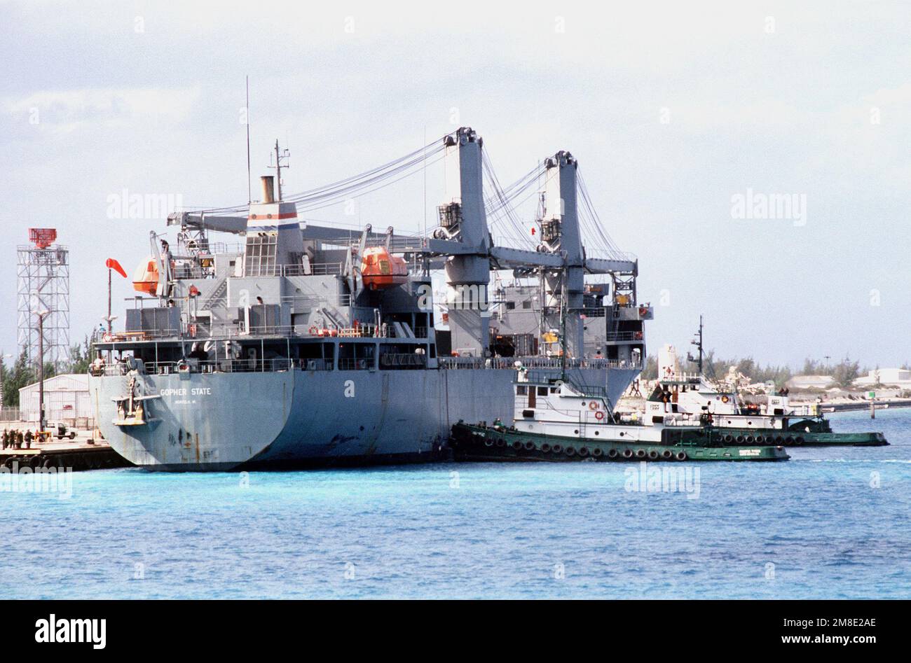 Tug boats push the Military Sealift Command auxiliary crane ship GOPHER ...