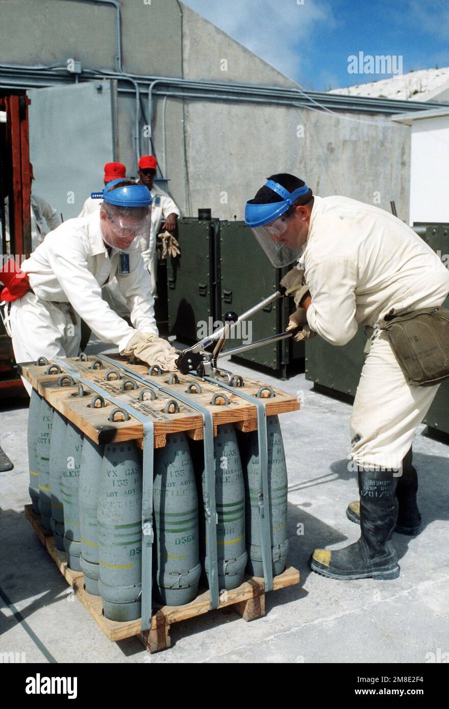 Two soldiers cut the bands on a pallet of 155mm chemical artillery ...
