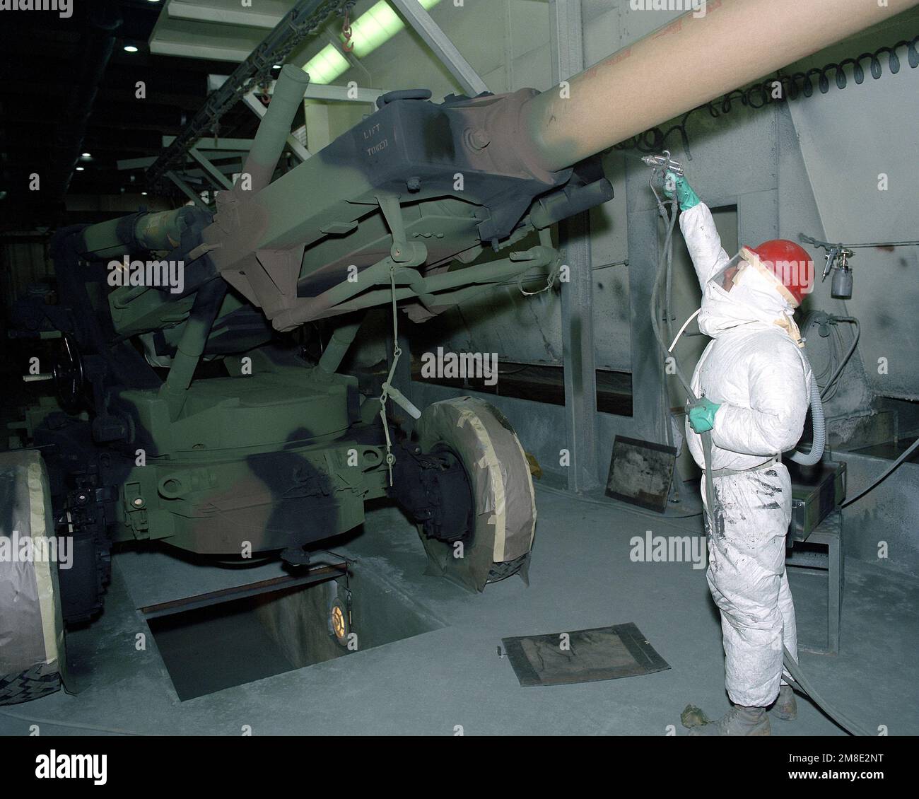 Toby Brown, a civilian employee, applies a coat of paint to the barrel ...