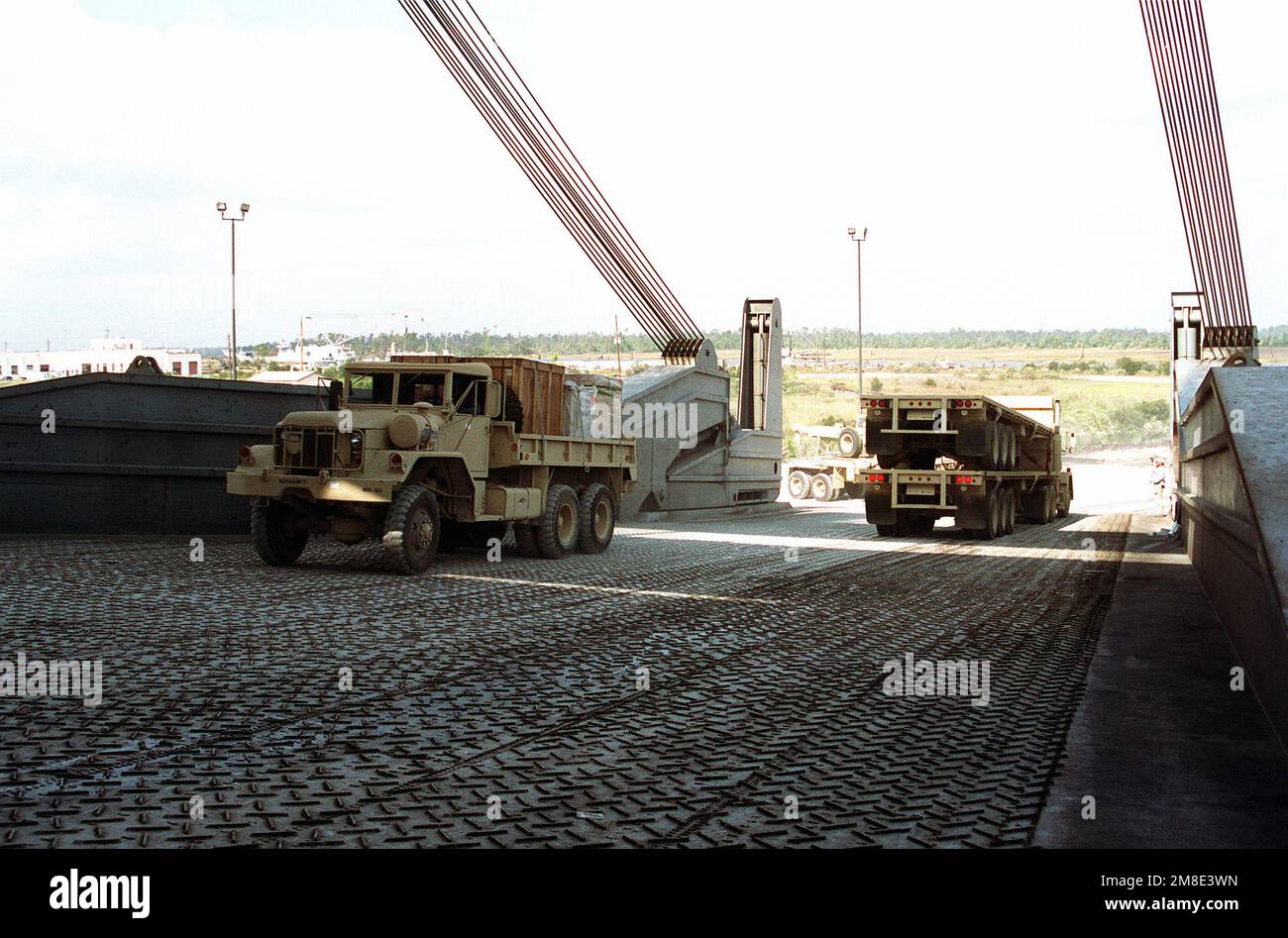 An M-54 5-ton cargo truck and a tractor trailer are driven onto the ...