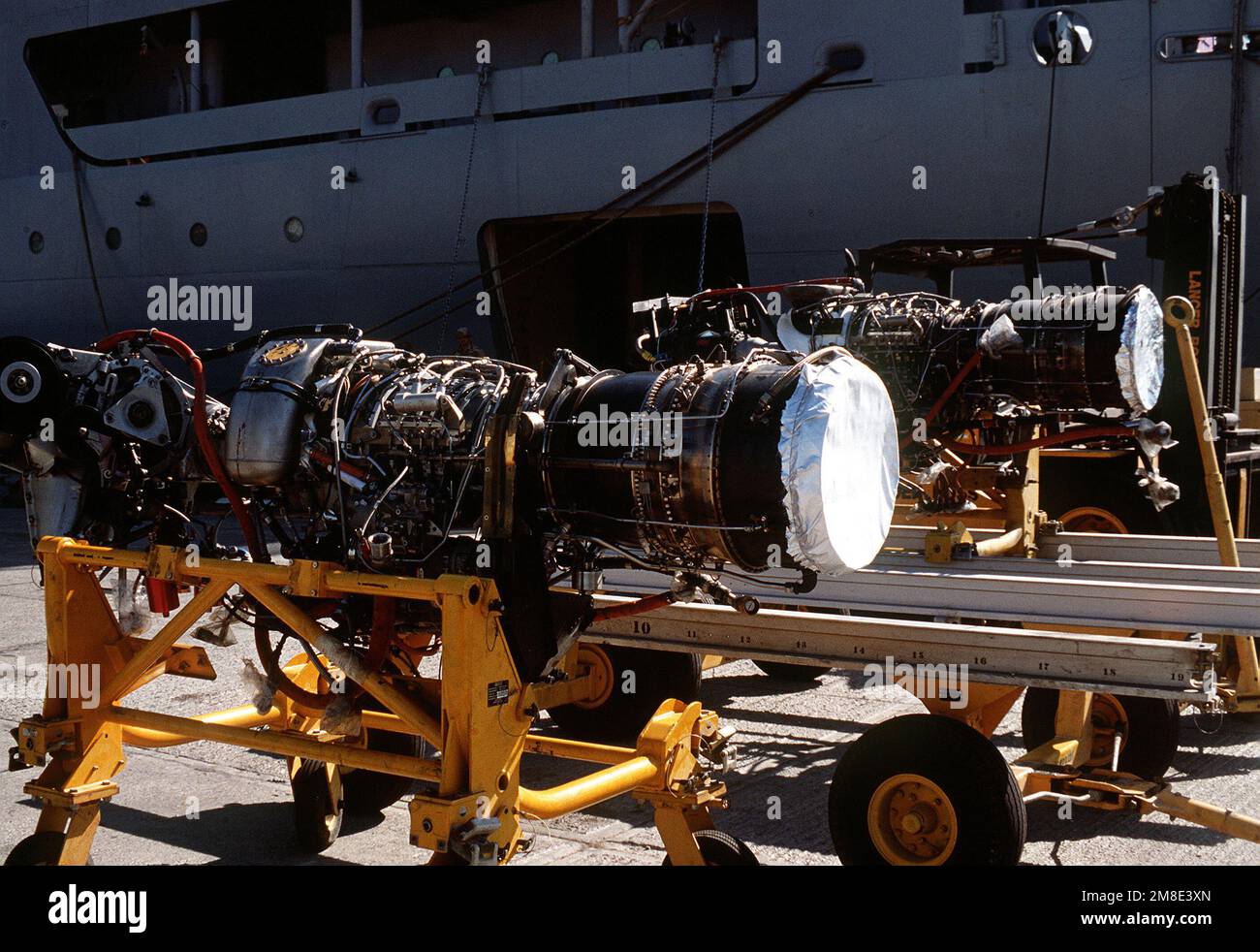 Jet engines sit on the pier beside the aviation logistic ship USNS ...