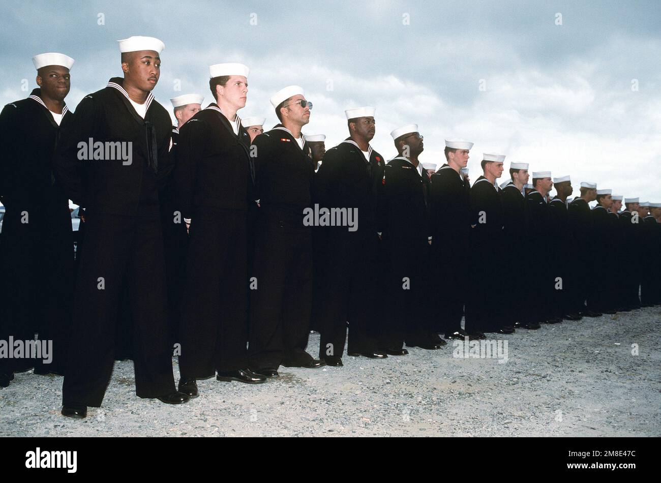 Members of the ship's crew stand at parade rest on the pier during the ...