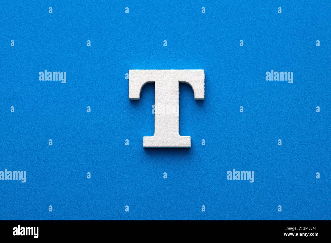 Alphabet letter T - White wooden letter on blue foamy background Stock ...