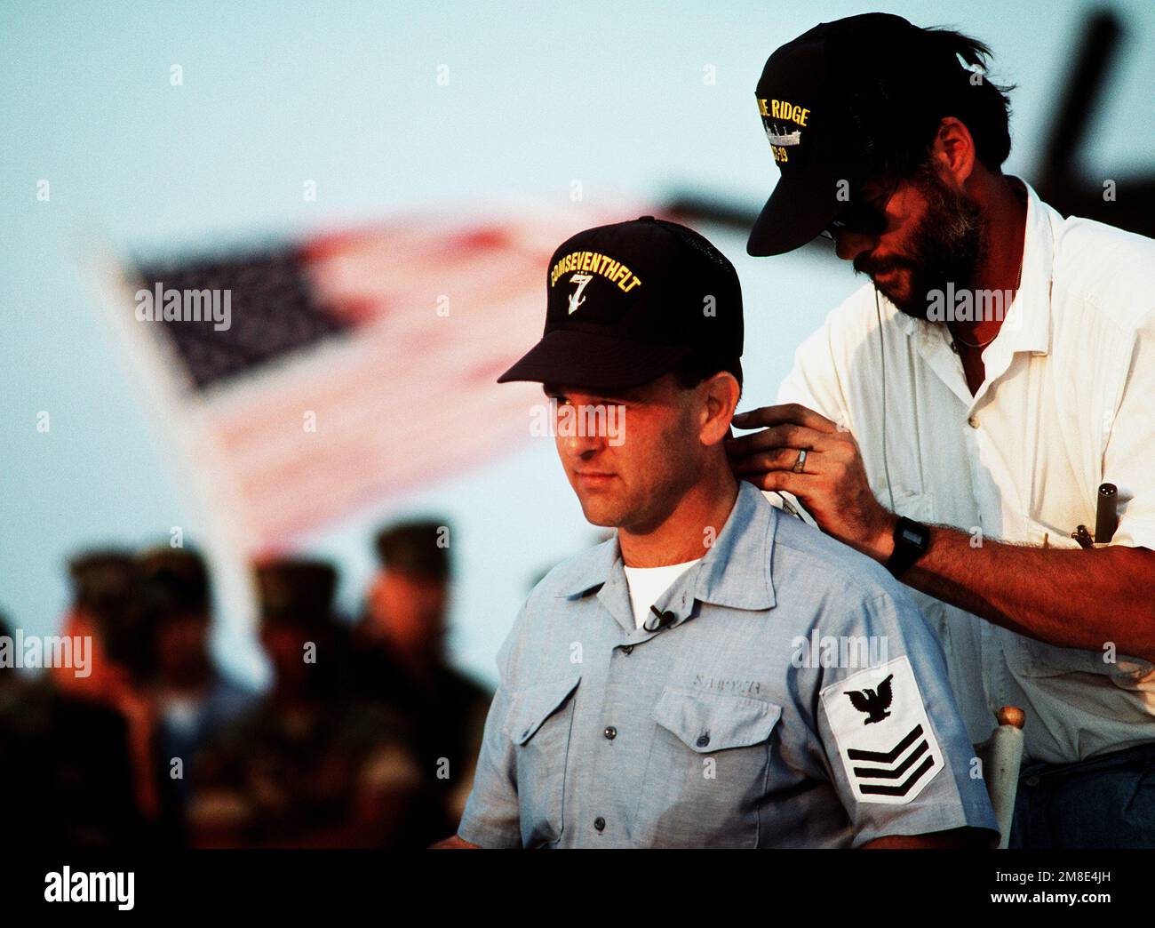 A sound technician connects microphone wires to a sailor prior to the ...