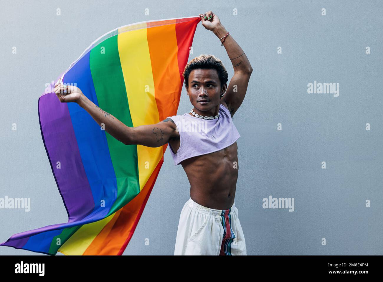 Stylish guy holding an LGBT rainbow flag walking and looking back Stock ...