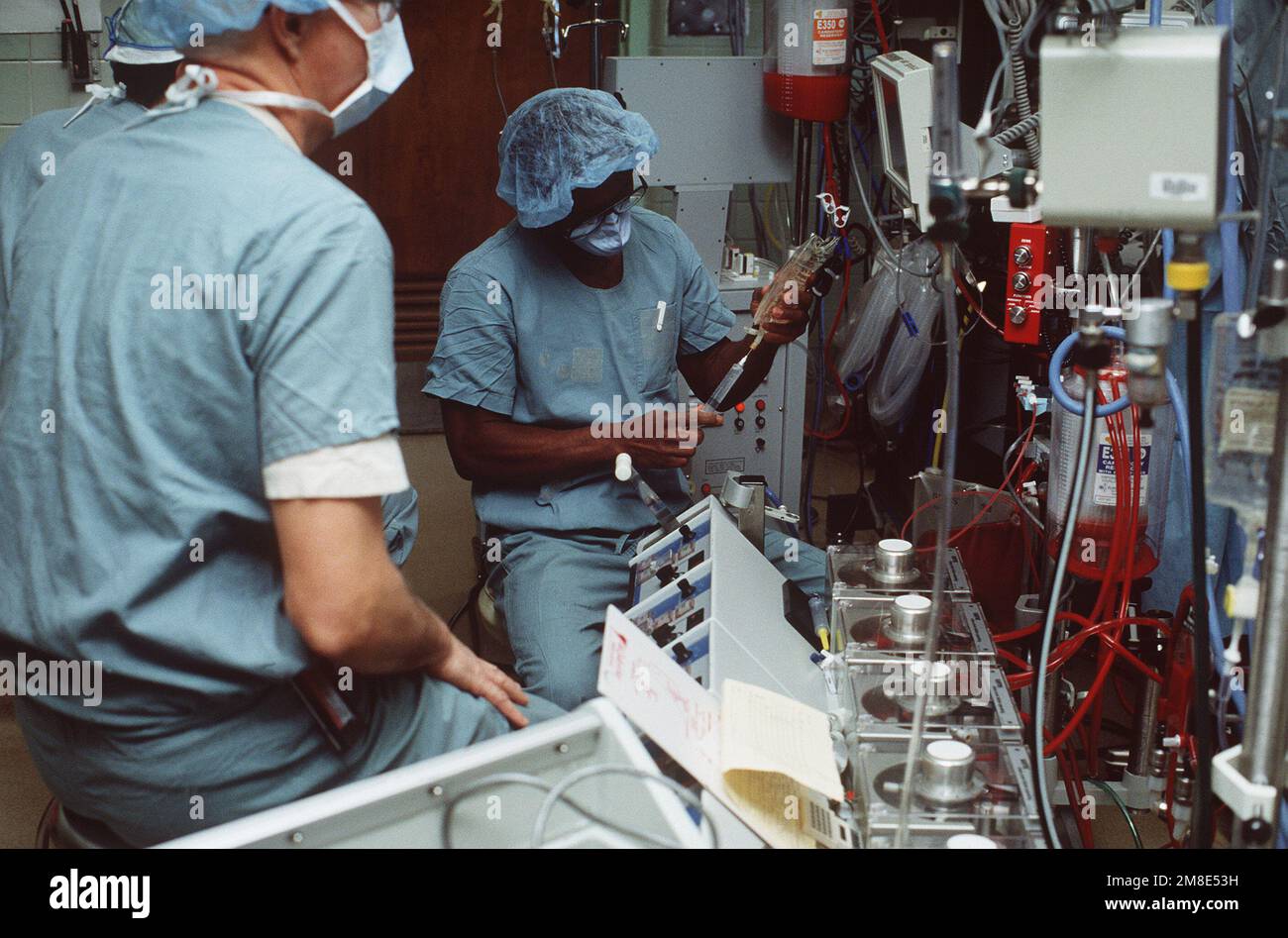 Technicians operate a heart/lung machine during open heart surgery at ...