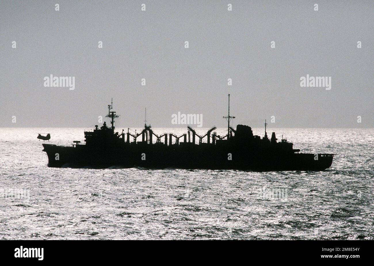 A CH-46 Sea Knight helicopter hovers near the fast combat support ship ...