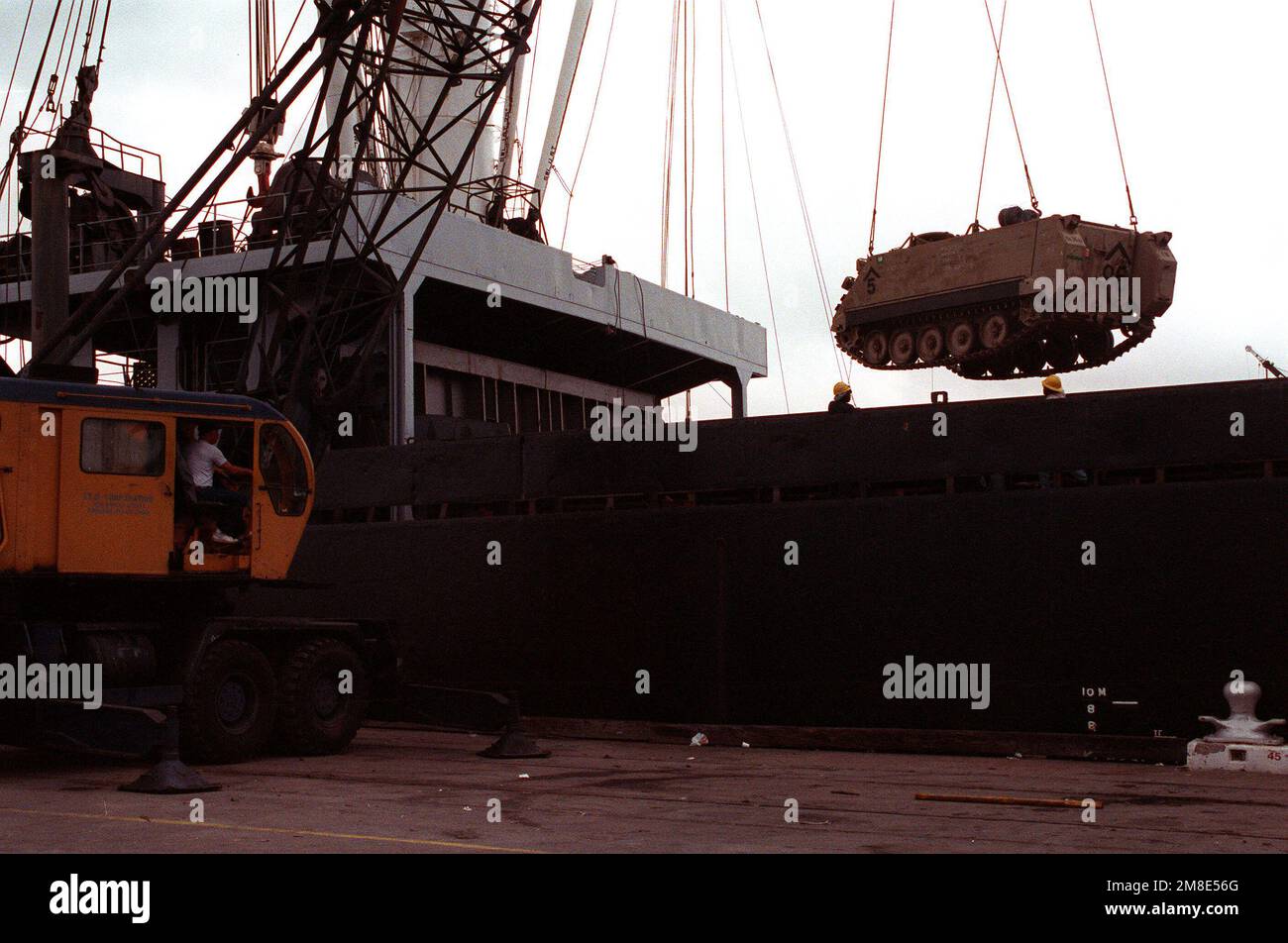 A crane lifts an M-113 armored personnel carrier onto the commercial ...