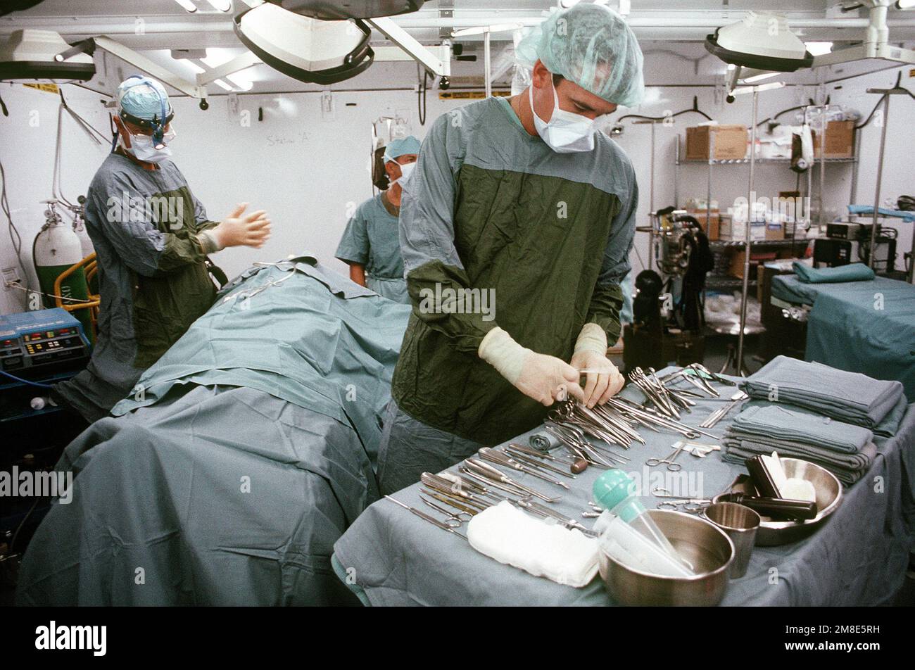 An assistant gets a pair of forceps for the doctor as a surgical team ...