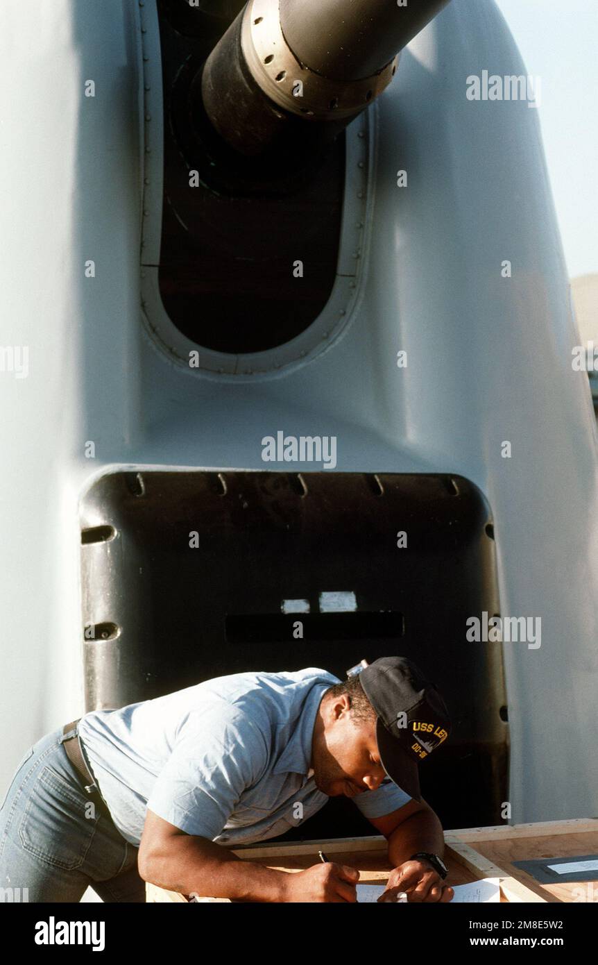 A sailor aboard the destroyer USS LEFTWICH (DD-984) leans on a crate in ...