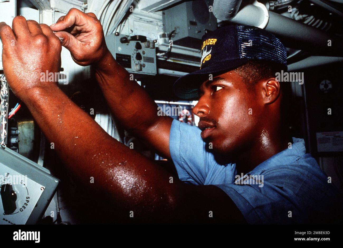 A sailor works on an electrical connection aboard the ocean minesweeper ...