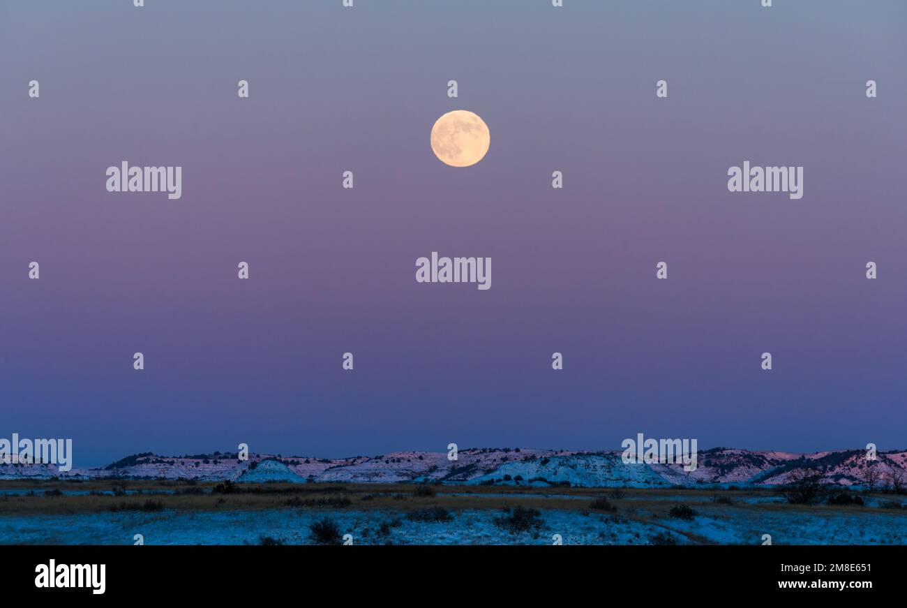 A full moon rising at sunset over a snowy landscape at Theodore ...