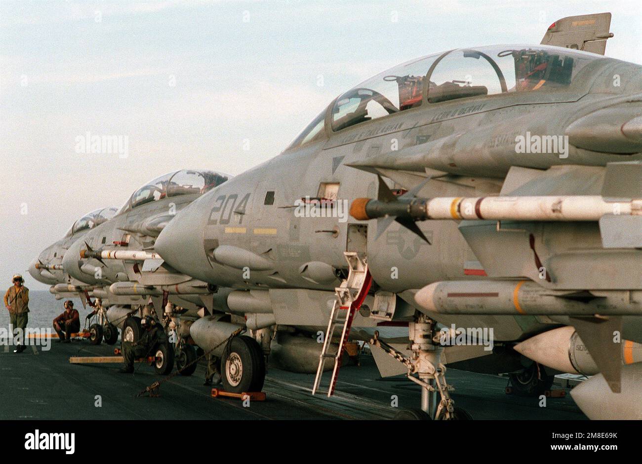 Three Fighter Squadron 103 (VF-103) F-14A Tomcat aircraft sit armed and ready on the flight deck ...