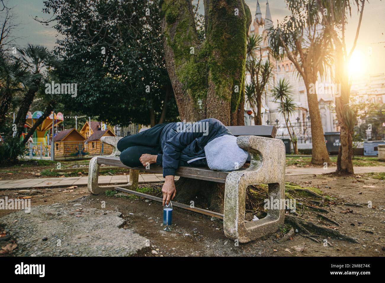 Homeless man or alcoholic sleeping on bench. Poor man on city street ...
