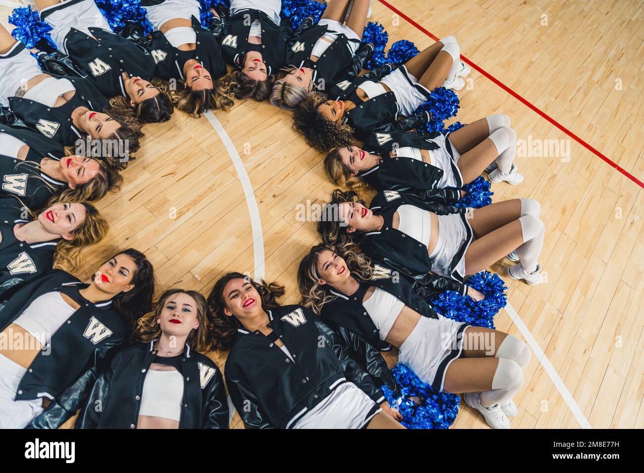 Group of cheerleaders lying on the floor forming a circle with their ...