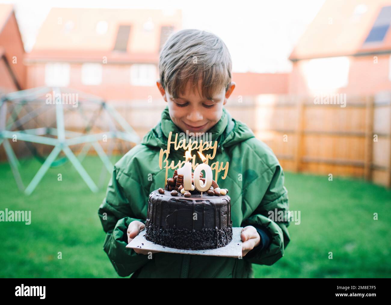 boy happily holding his 10th birthday cake with candles at home Stock ...