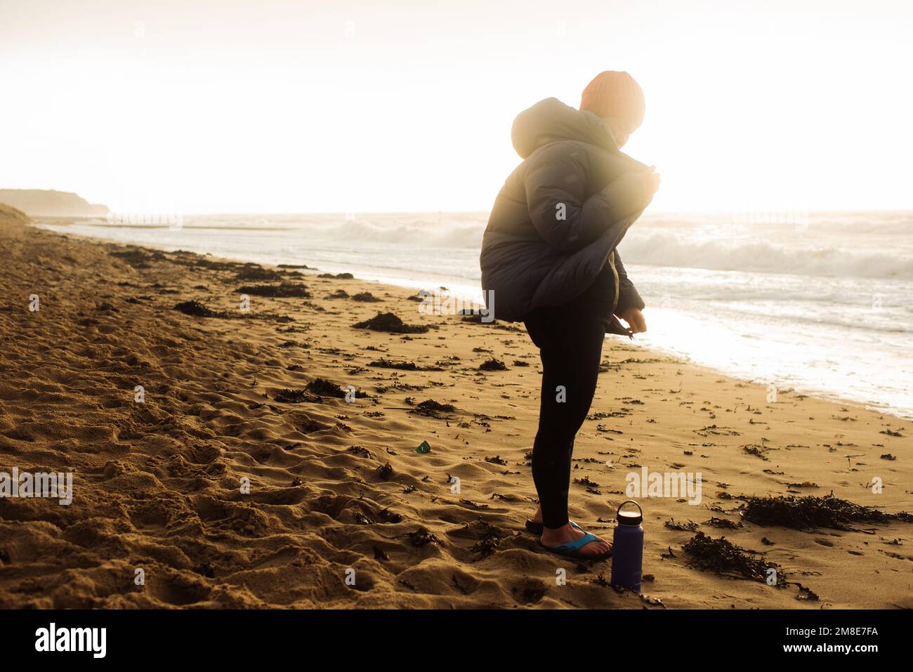 Asian woman getting changed on the beach ready for a cold water swim ...