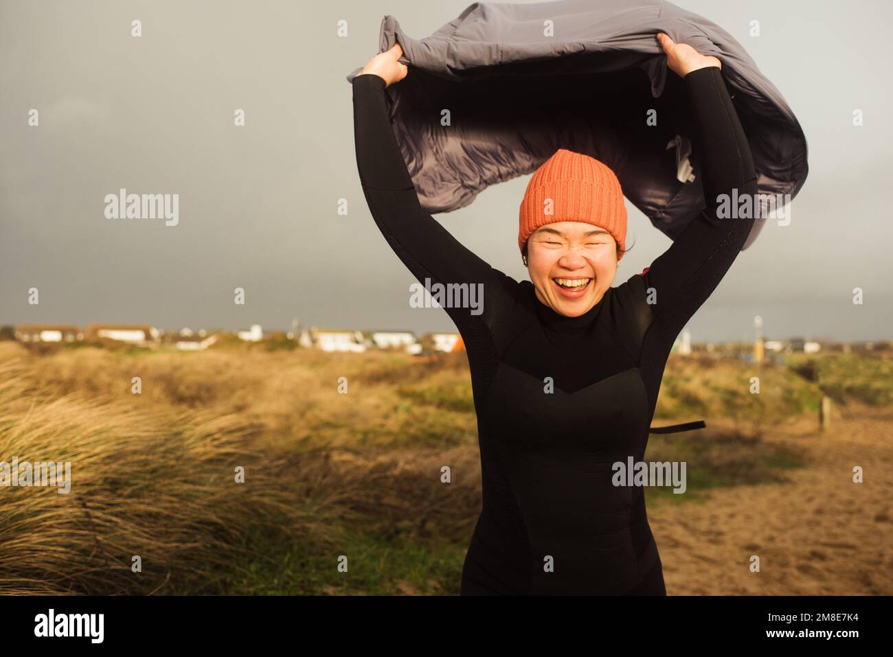 Asian woman running into the sea with her coat blowing in the wind ...