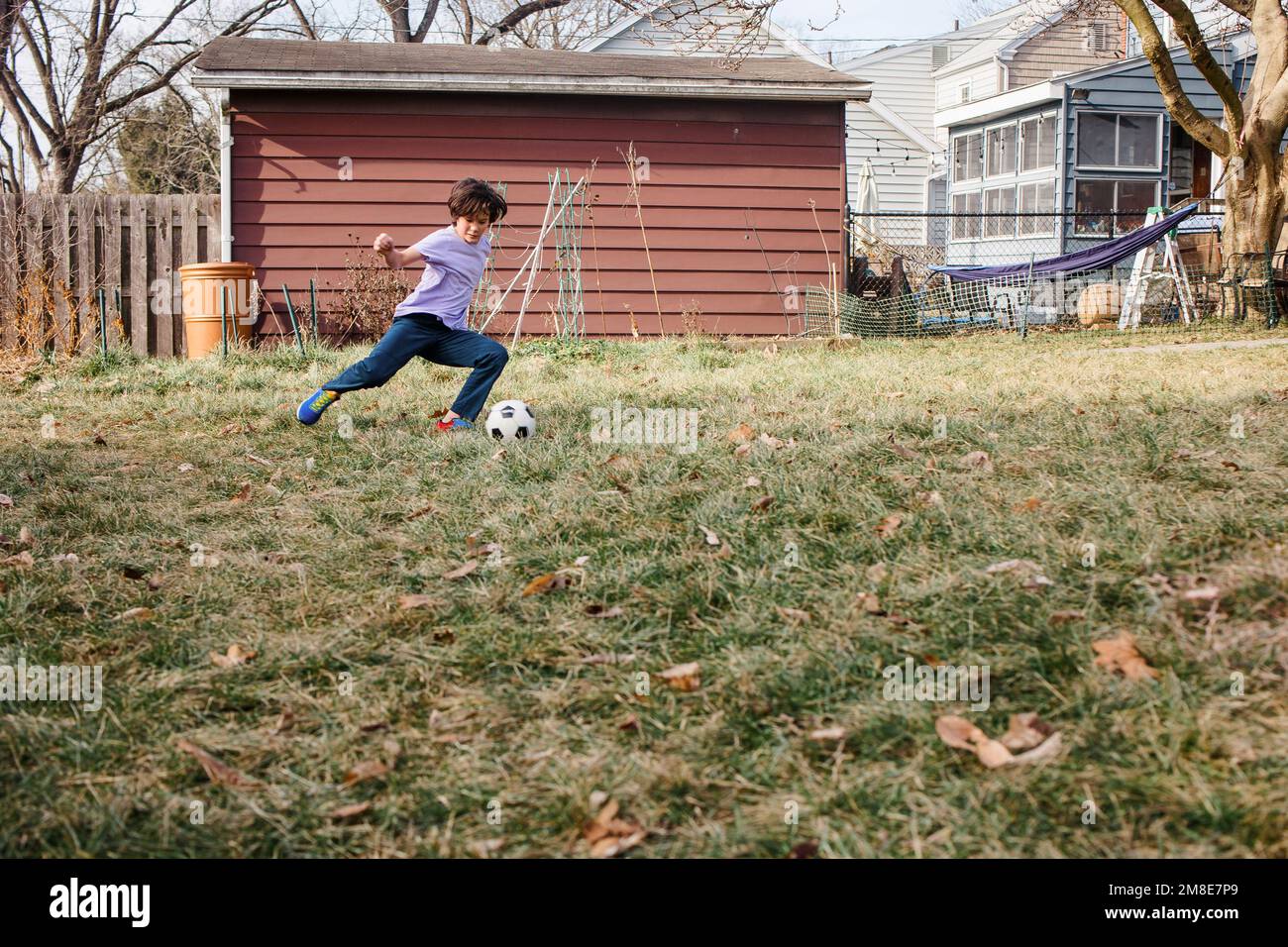 An athletic boy kicks soccer ball alone in backyard Stock Photo - Alamy