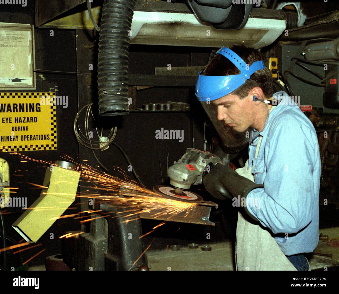 Fireman Apprentice Eric Smith grinds a piece of metal in the metal shop ...