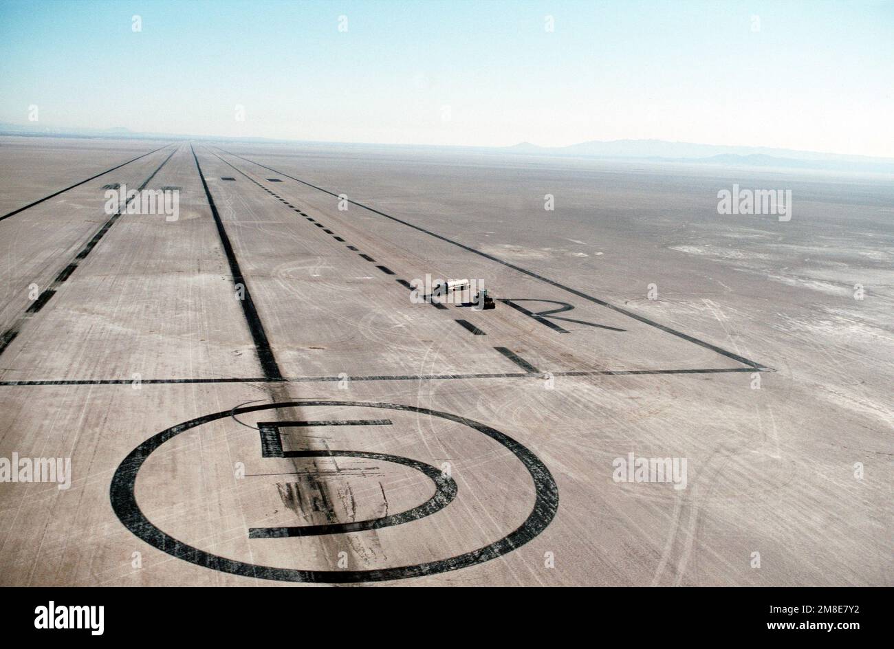 Maintenance vehicles cross the end of Runway 5 on Rogers Dry Lake. The ...