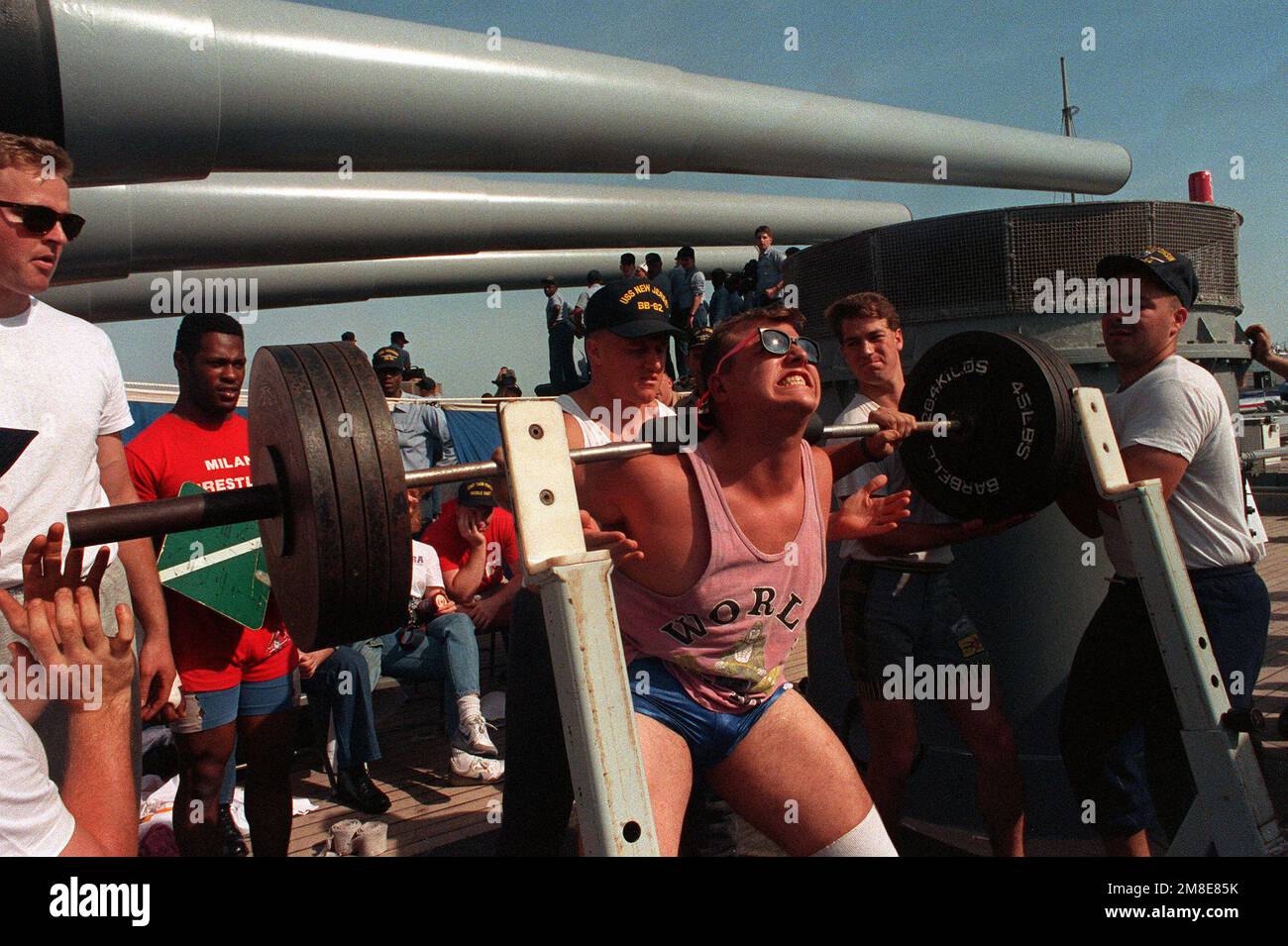 Spotters stand ready to assist a participant in a power-lifting ...