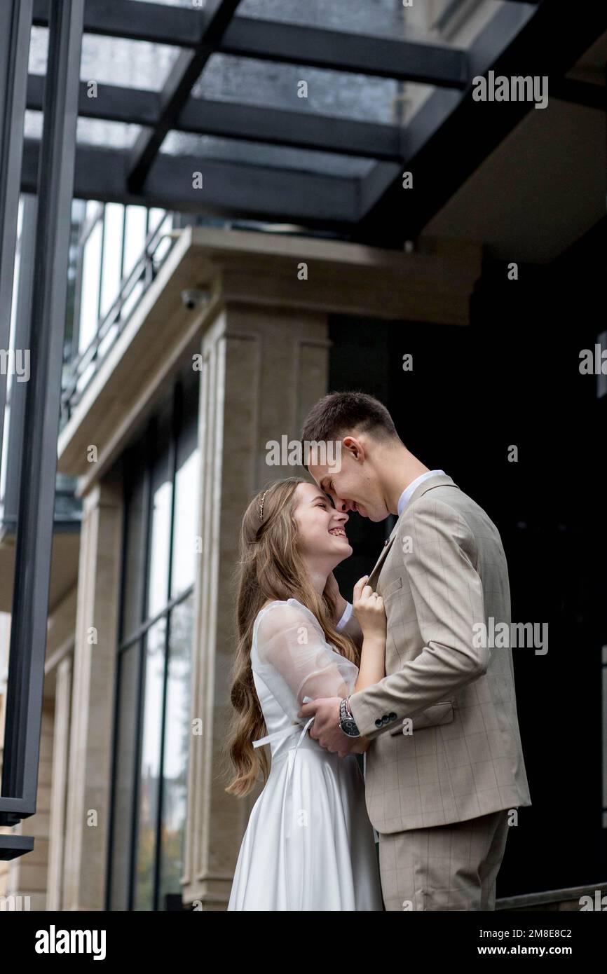 The bride looks at the groom with loving eyes. Smiling newlyweds look ...