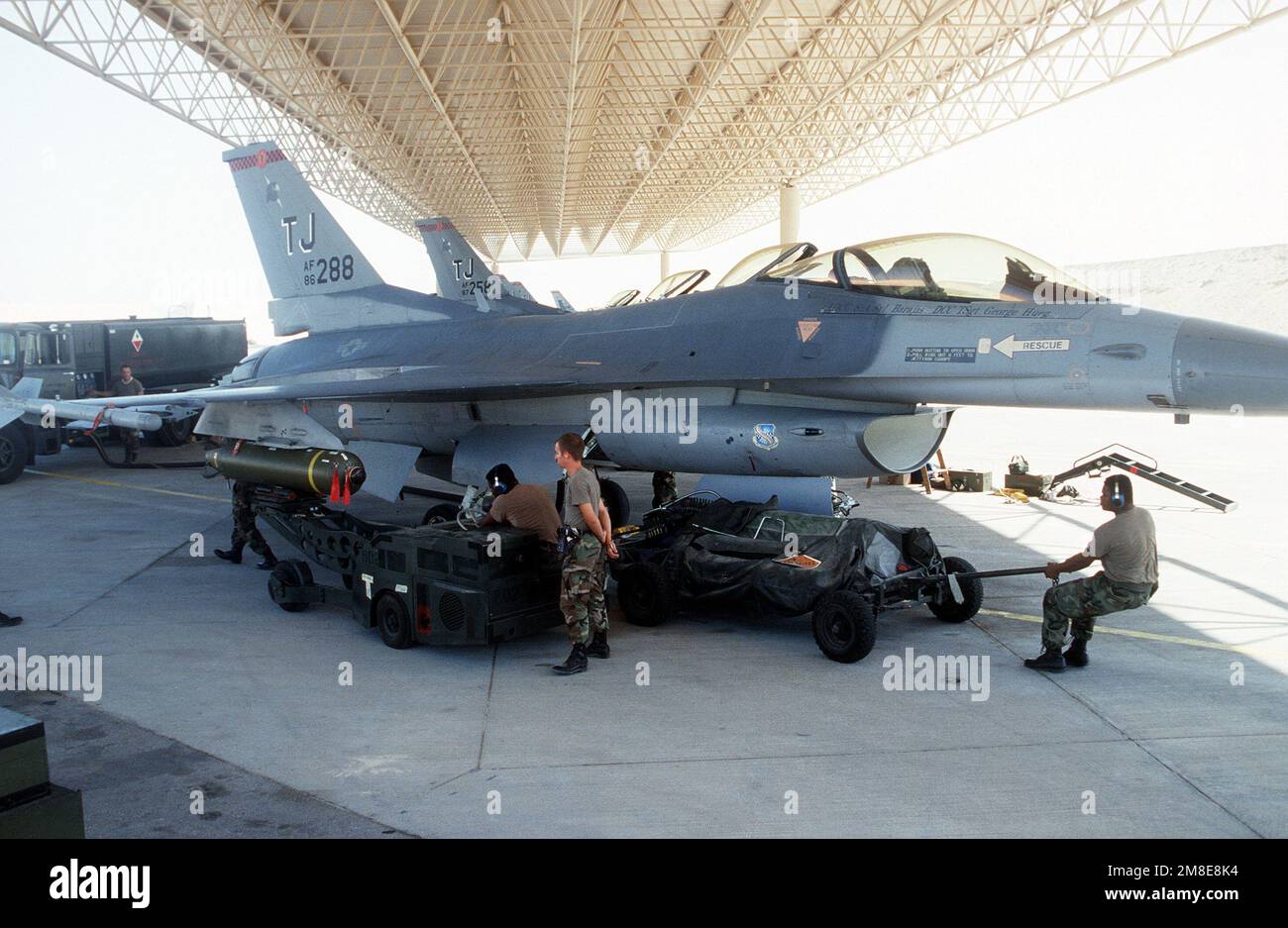 Munitions loading crews put a MK-20 Rockeye anti-armor bomb on the wing of a F-16 Falcon from ...