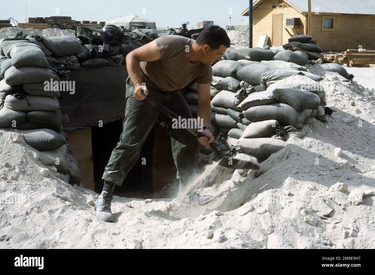 A Seabee from Naval Mobile Construction Battalion 74 shovels sand away ...