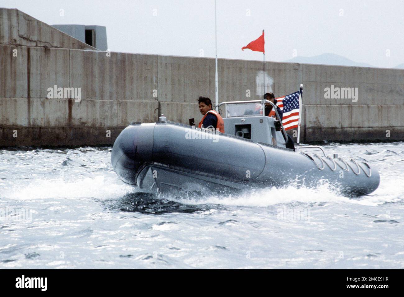 Sailors in a rigid-hull inflatable boat patrol the harbor during the ...