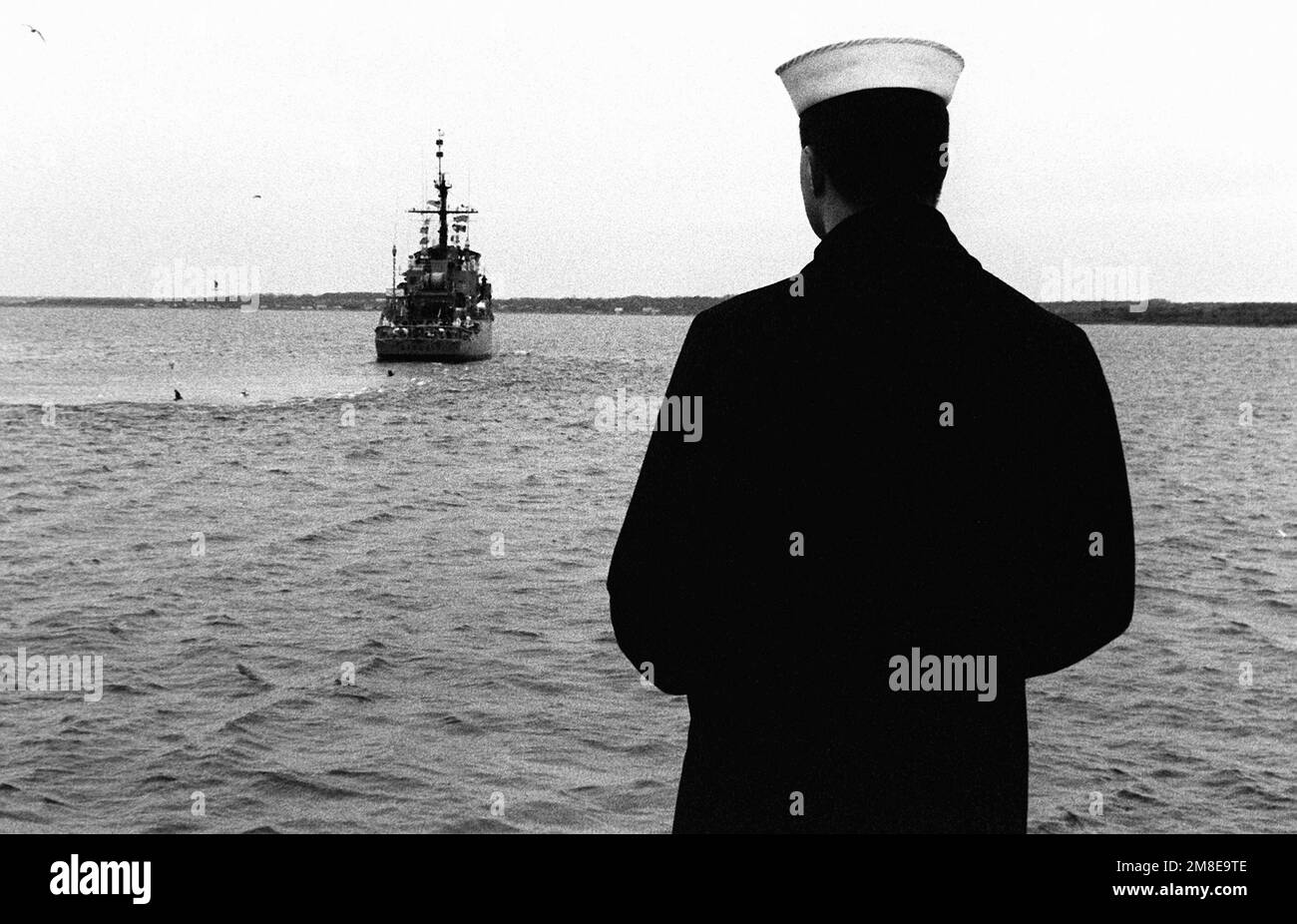 A sailor watches as the ocean minesweeper USS EXPLOIT (MSO-440) departs ...