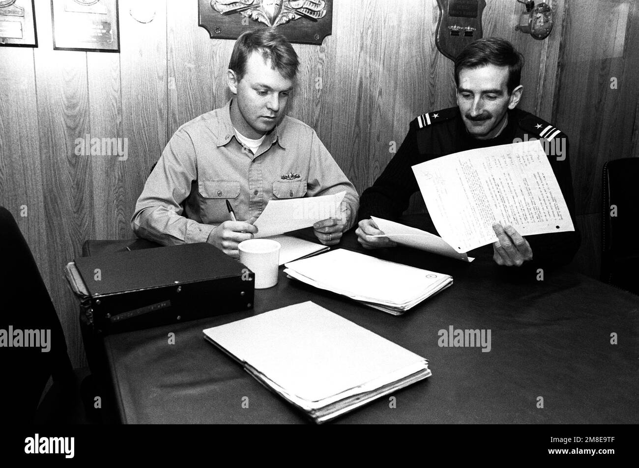 Officers aboard the ocean minesweeper USS EXPLOIT (MSO-440) review ...