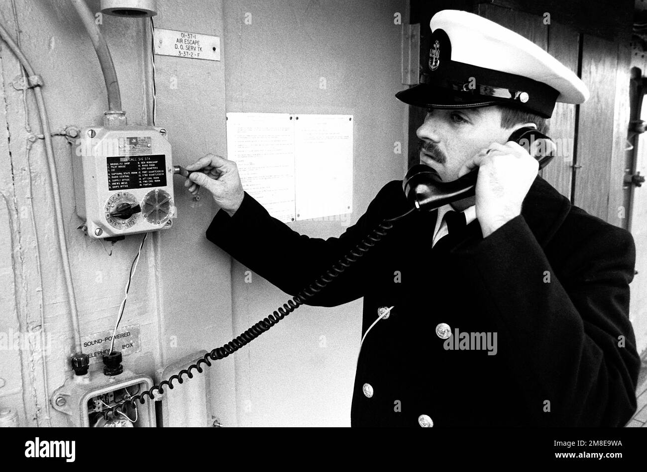 A chief petty officer uses a sound-powered phone to communicate with ...