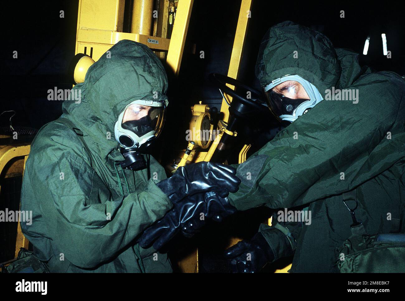 A crew member adjusts his companion's nuclear-biological-chemical ...