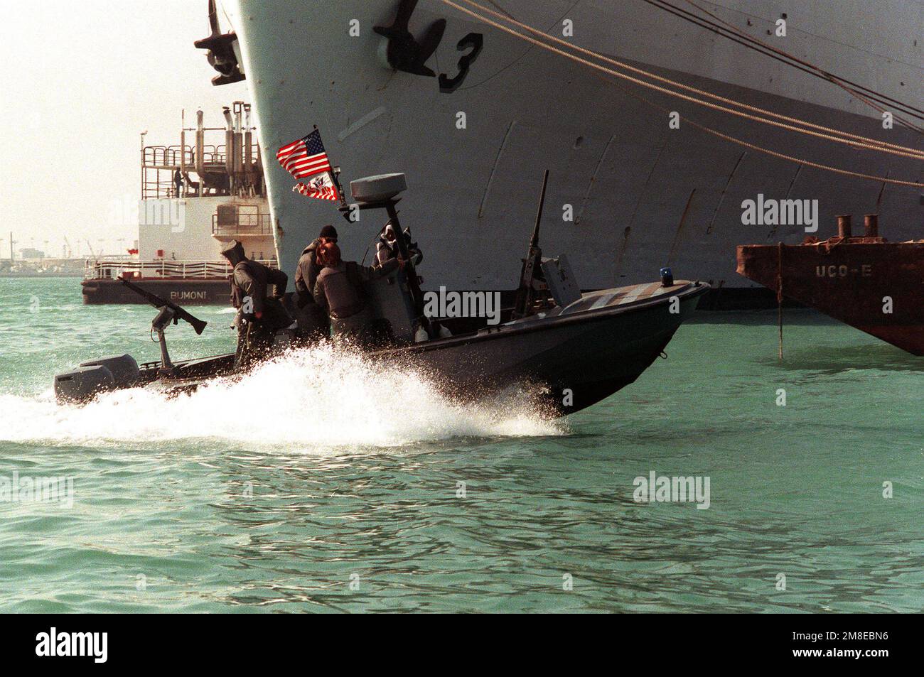 Coast Guard security personnel in a Sea Raider utility craft pass the ...