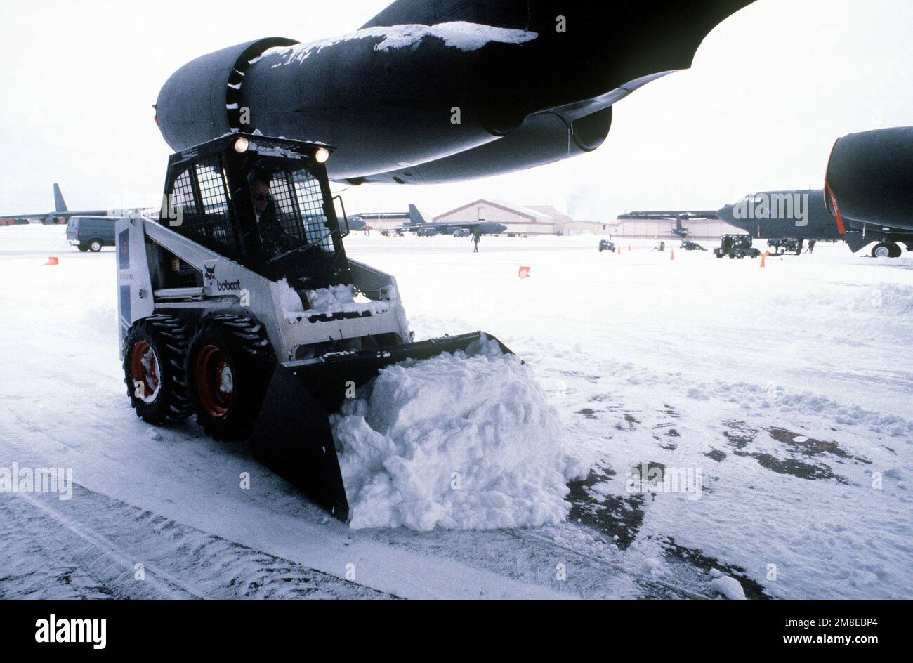 An airman clears snow from beneath the wing of a B-52H Stratofortress ...